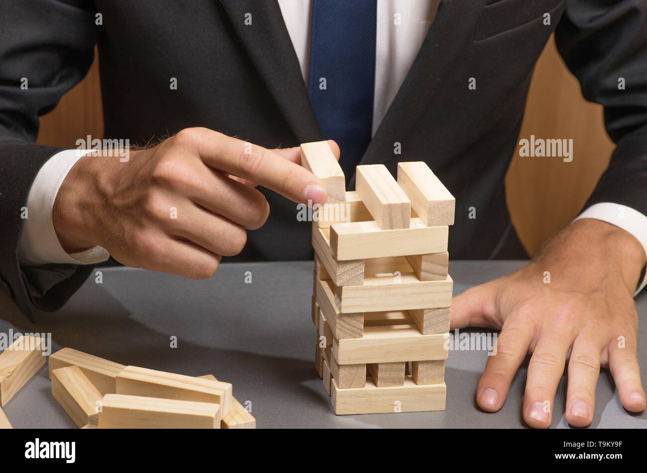 Businessman in business suit building a tower of wooden blocks ...