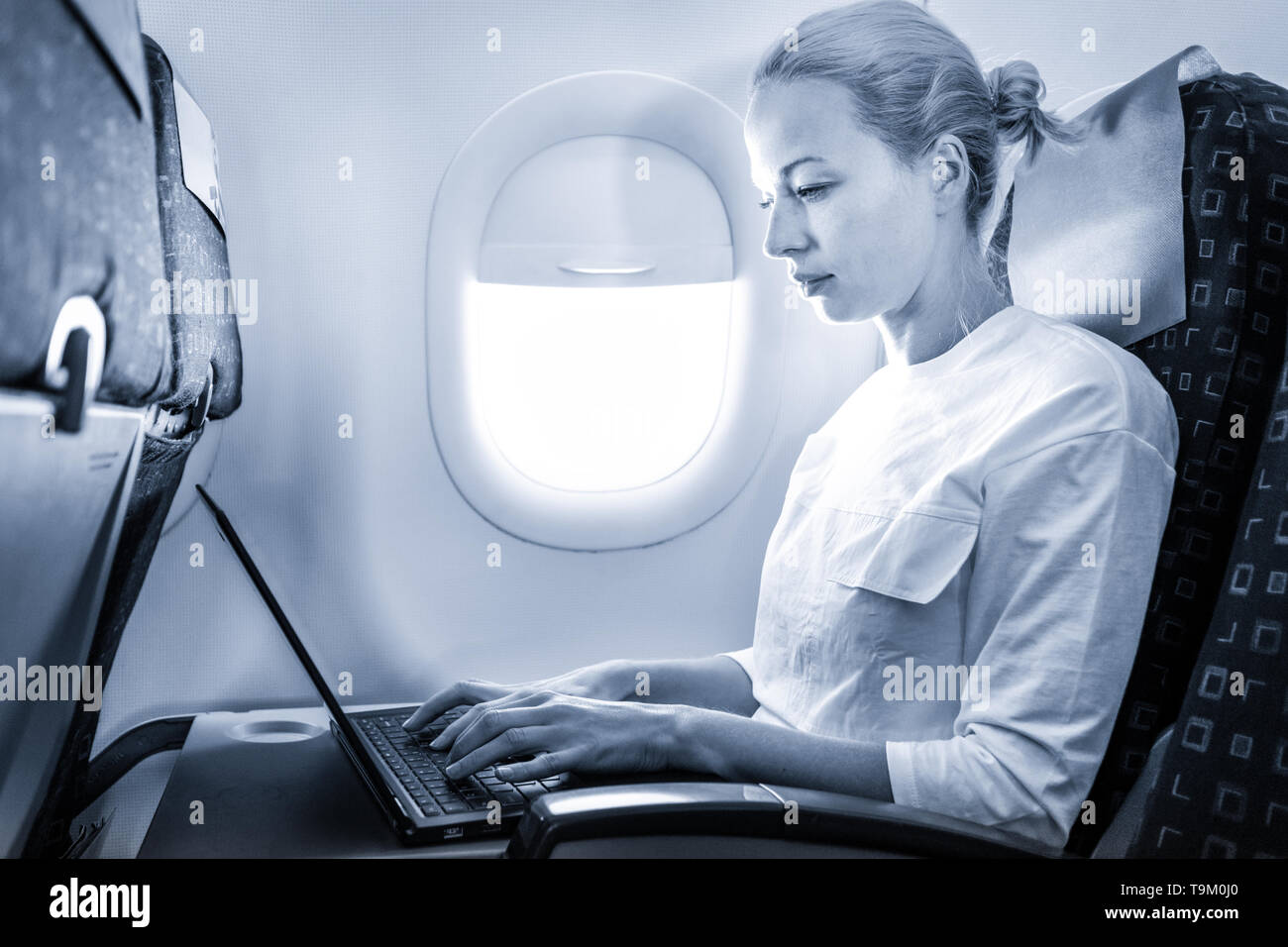Attractive caucasian female passenger working at modern laptop computer ...