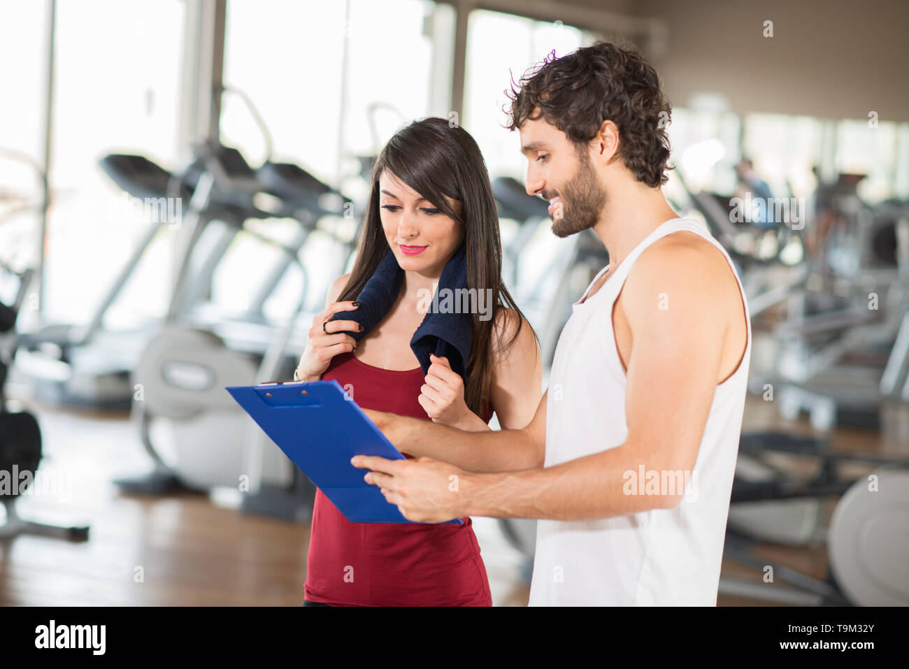 Woman talking to her personal trainer in a gym Stock Photo - Alamy