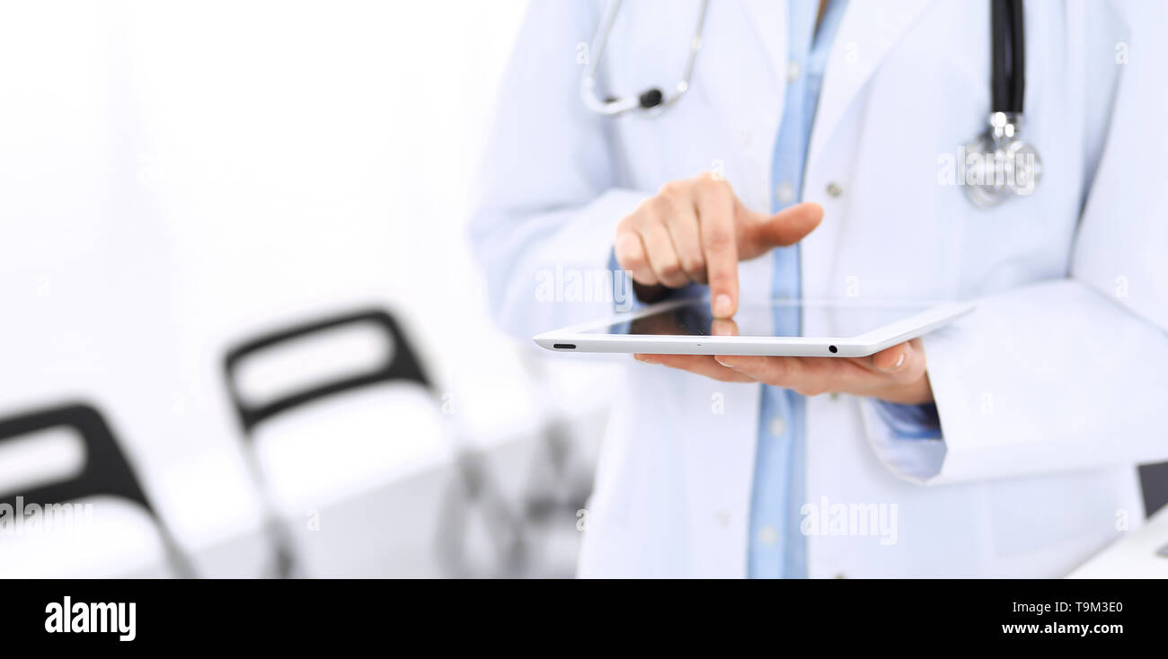 Female physician using digital tablet while standing near reception ...