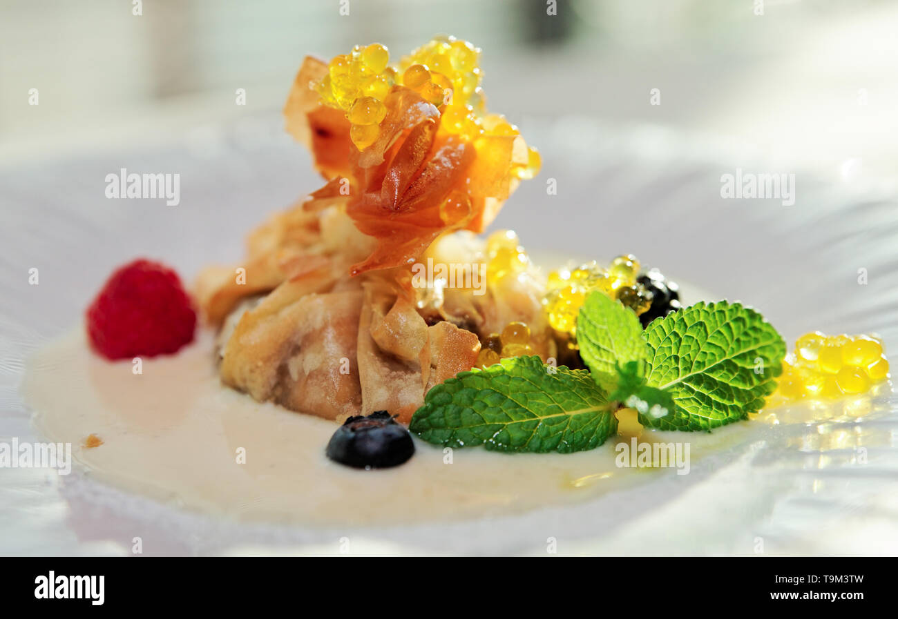 Apple strudel with molecular sweet caviar and berries, back sunlight ...