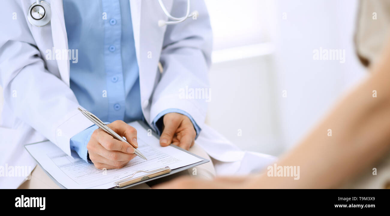 Doctor and patient talking. Physician at work in hospital while writing ...