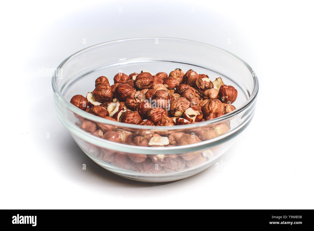 Isolated crystal bowl with hazelnuts against white background. Peeled ...