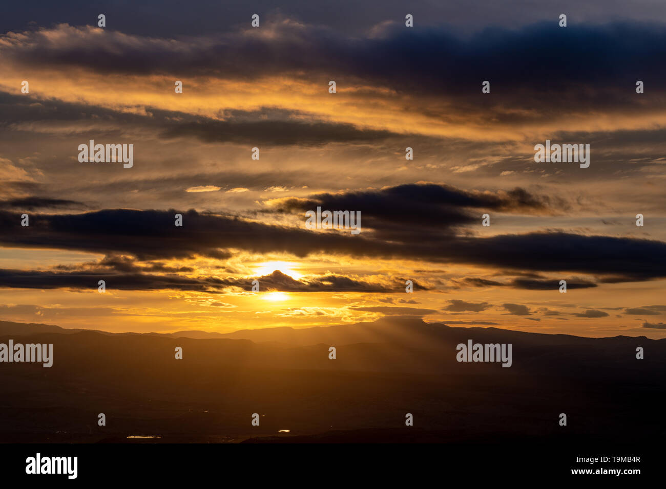 Warm colors of sunrise as they shine through dark clouds Stock Photo ...