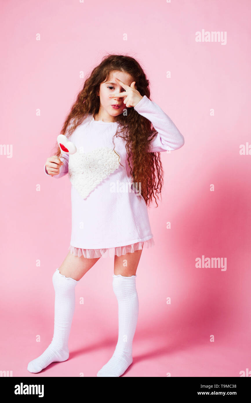 little cute girl with candy on pink background posing emotional ...