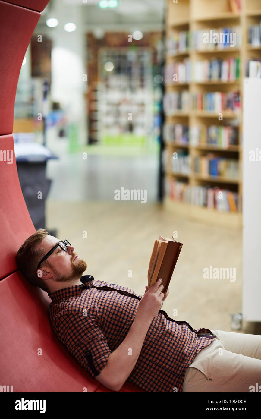 Bearded man reading book in library Stock Photo - Alamy
