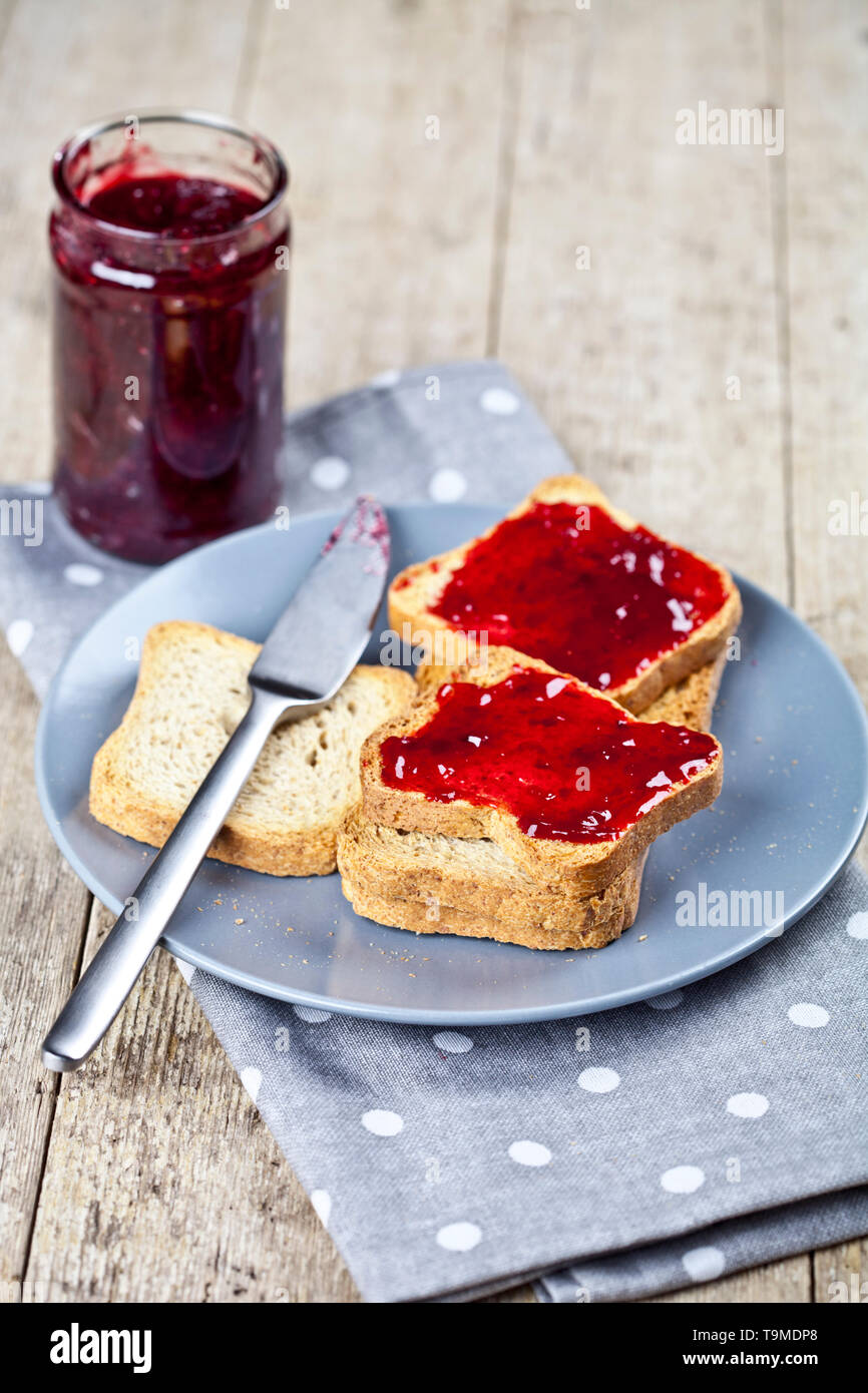 Toasted cereal bread slices on grey plate and jar with homemade cherry ...
