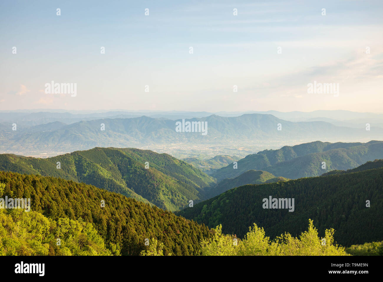 Aerial view of forested mountains with sprawling valley town in ...