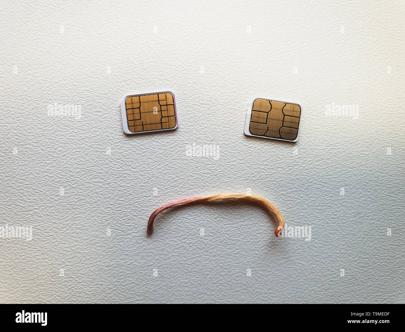 two micro sim cards lying in the shape of a sad face Stock Photo - Alamy