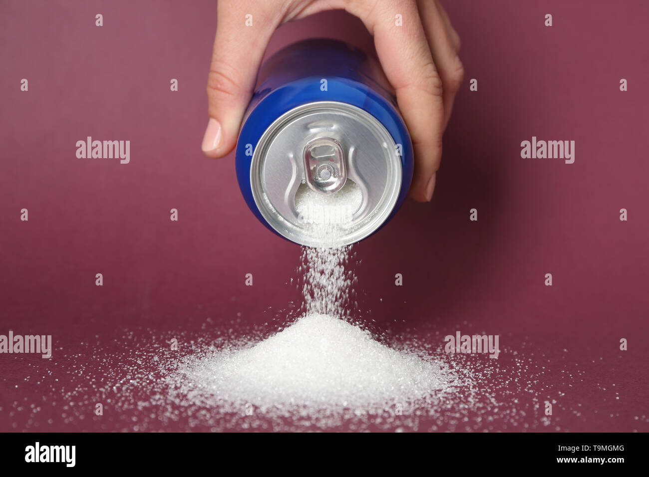 Woman pouring sugar from can on color background Stock Photo - Alamy