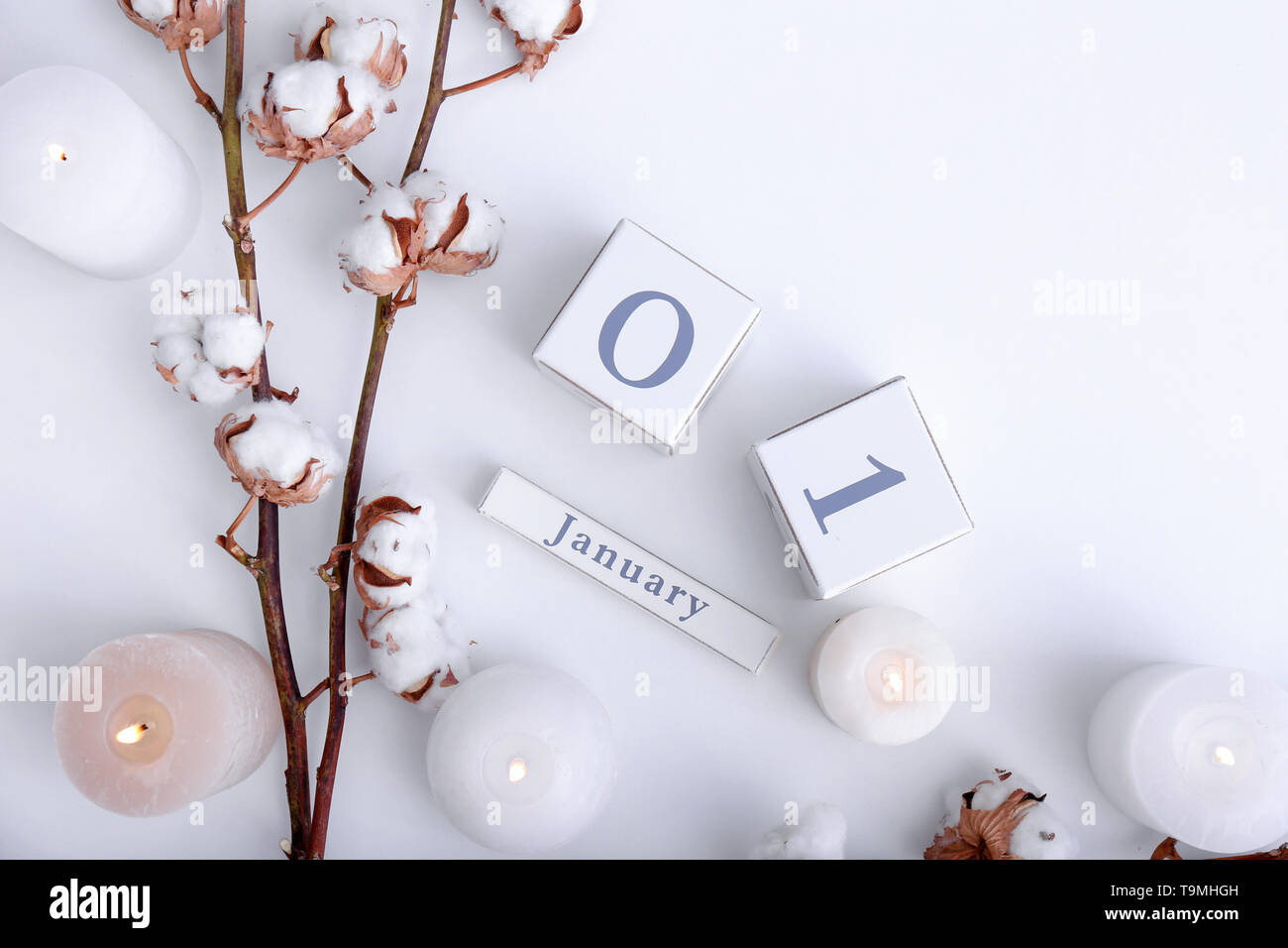 Cotton flowers, burning candles and date JANUARY, 1 on white background ...