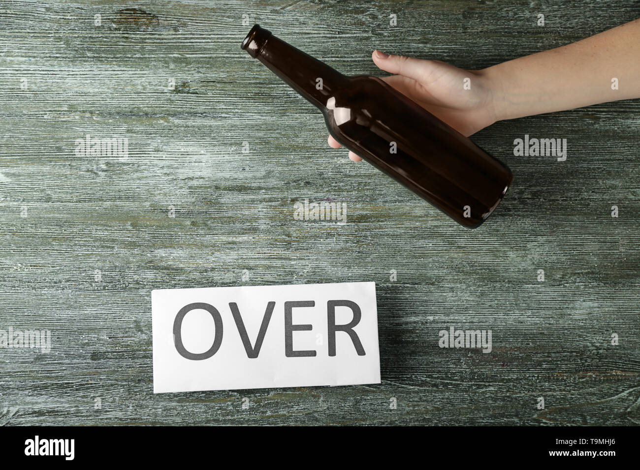 Paper sheet with word OVER and female hand with bottle of beer on ...