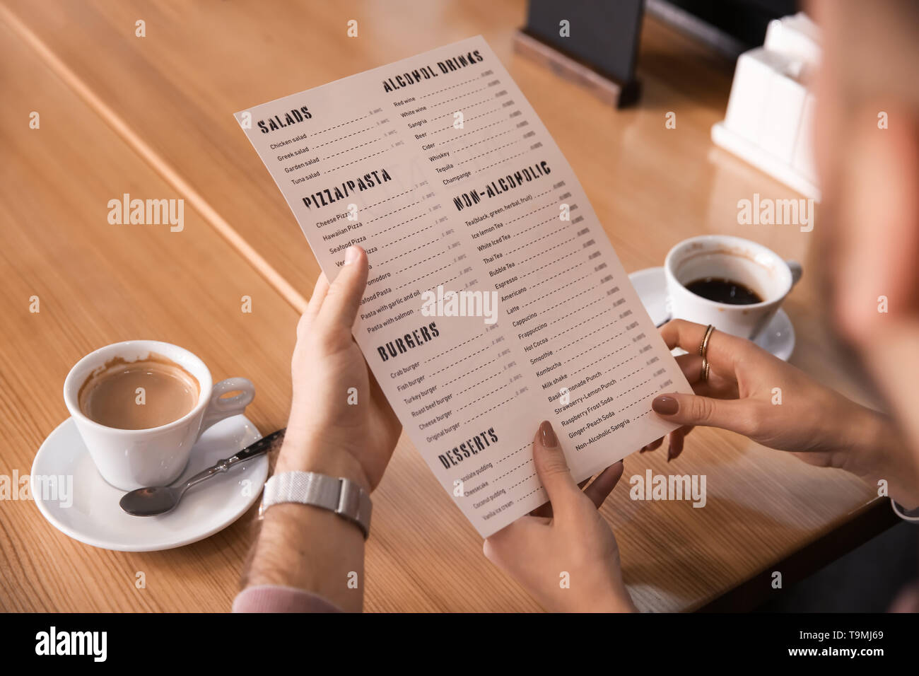 Young couple looking through menu in restaurant Stock Photo - Alamy