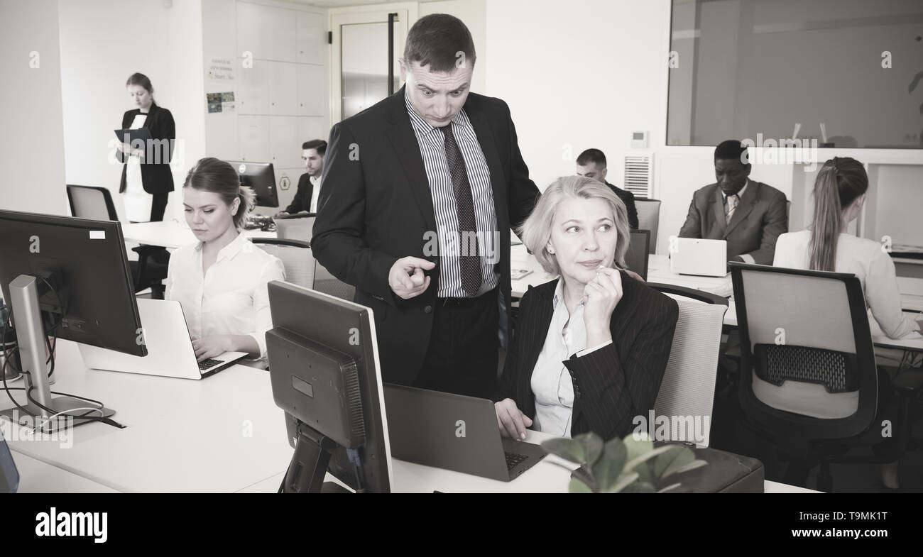 Upset mature woman sitting at laptop in coworking space while ...