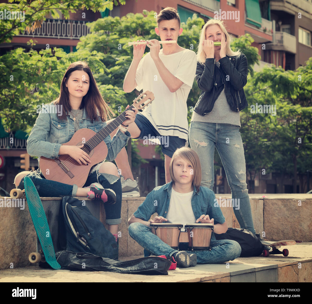 Portrait of four smiling teenage friends playing music together ...