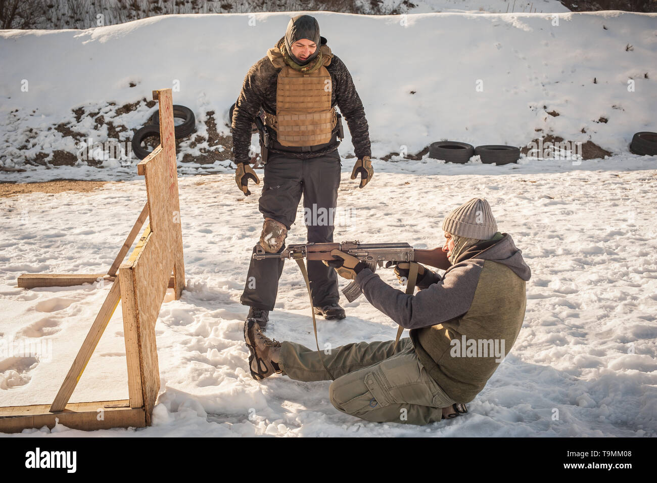 Instructor demonstrate body position of combat rifle shooting at winter ...