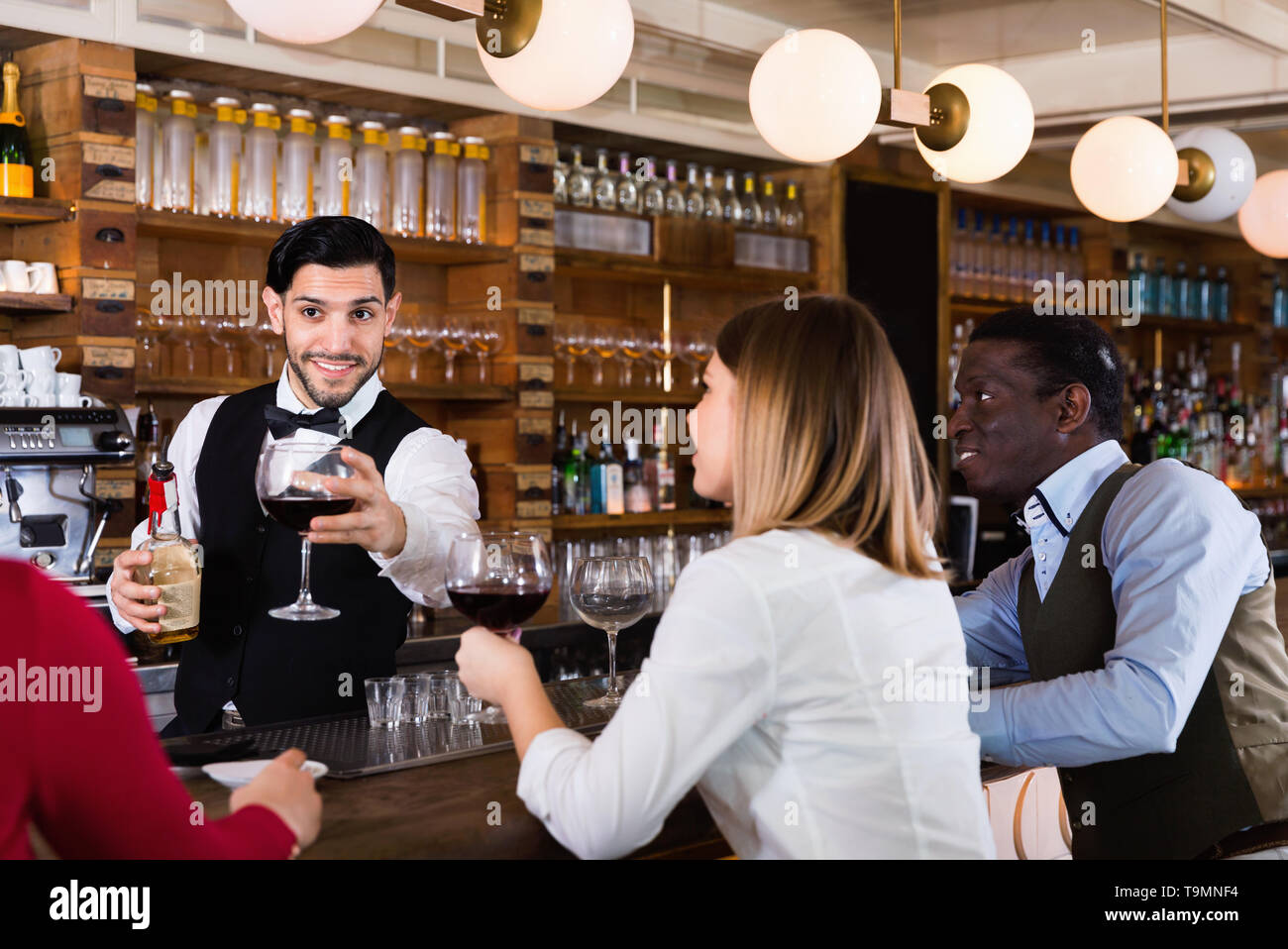 Portrait of positive smiling barman and cheerful glad people who are ...