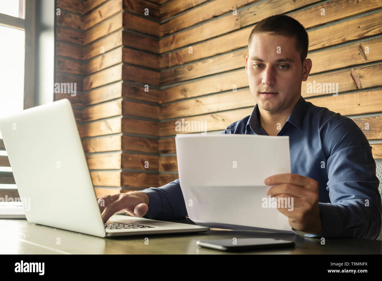 Concerned businessman reading a paper document or letter gesturing with ...