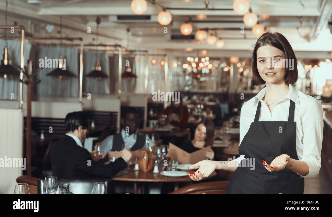 Portrait of smiling female waiter who is standing in luxurious ...