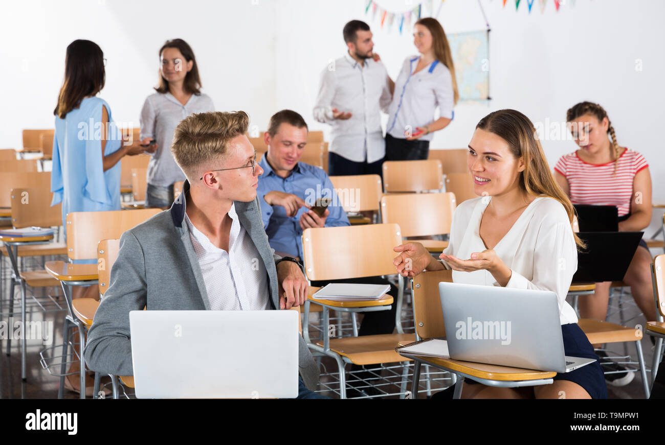 Happy group of adult students lively chatting while enjoying free time ...