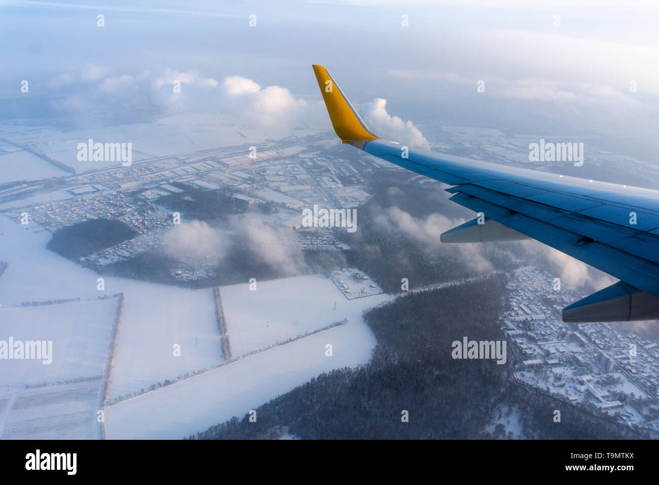 Snow covered land and cloud seen through window, airplane wing from ...
