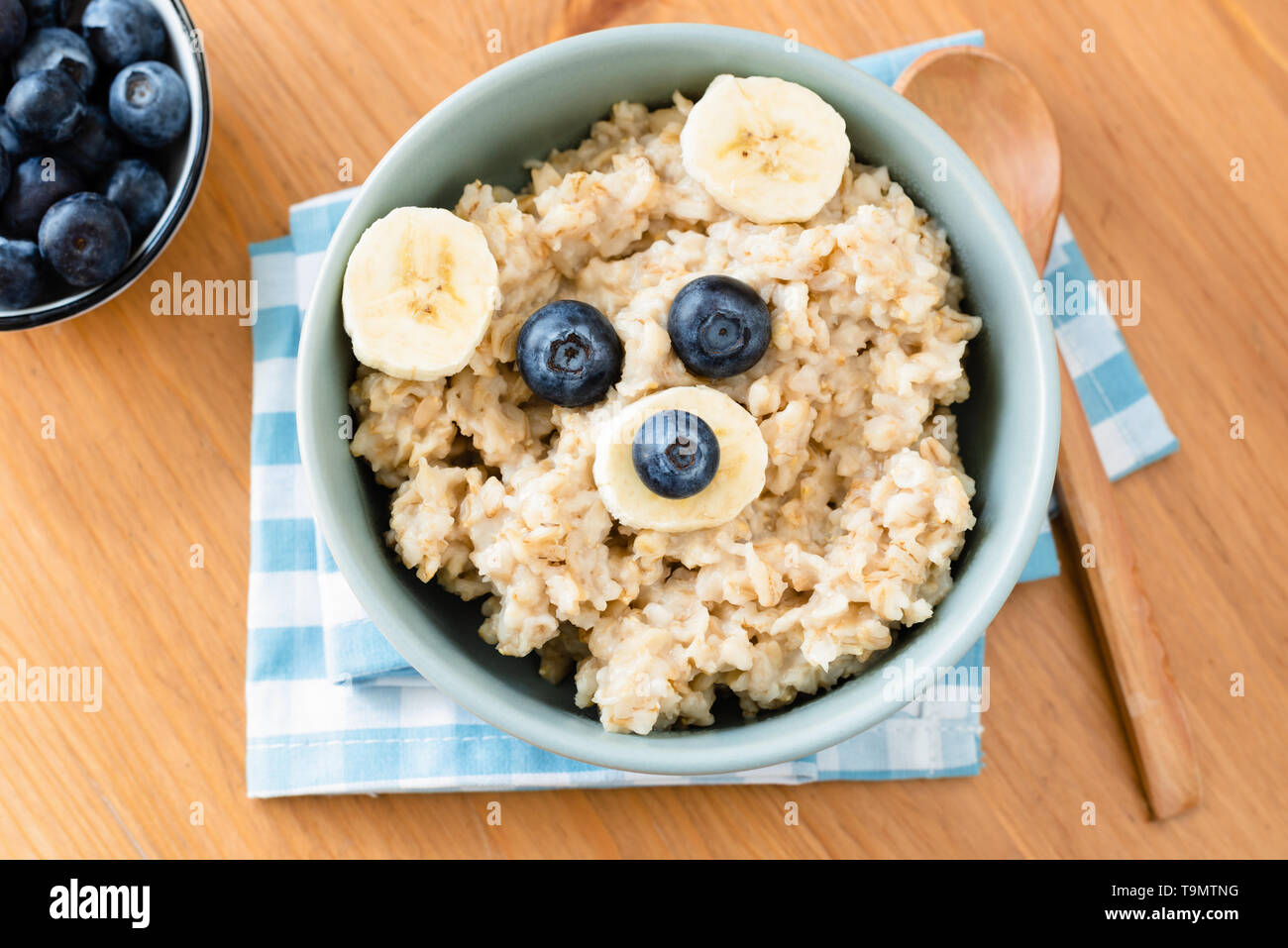 Oatmeal porridge with funny animal face in a bowl. Table top view. Kids ...