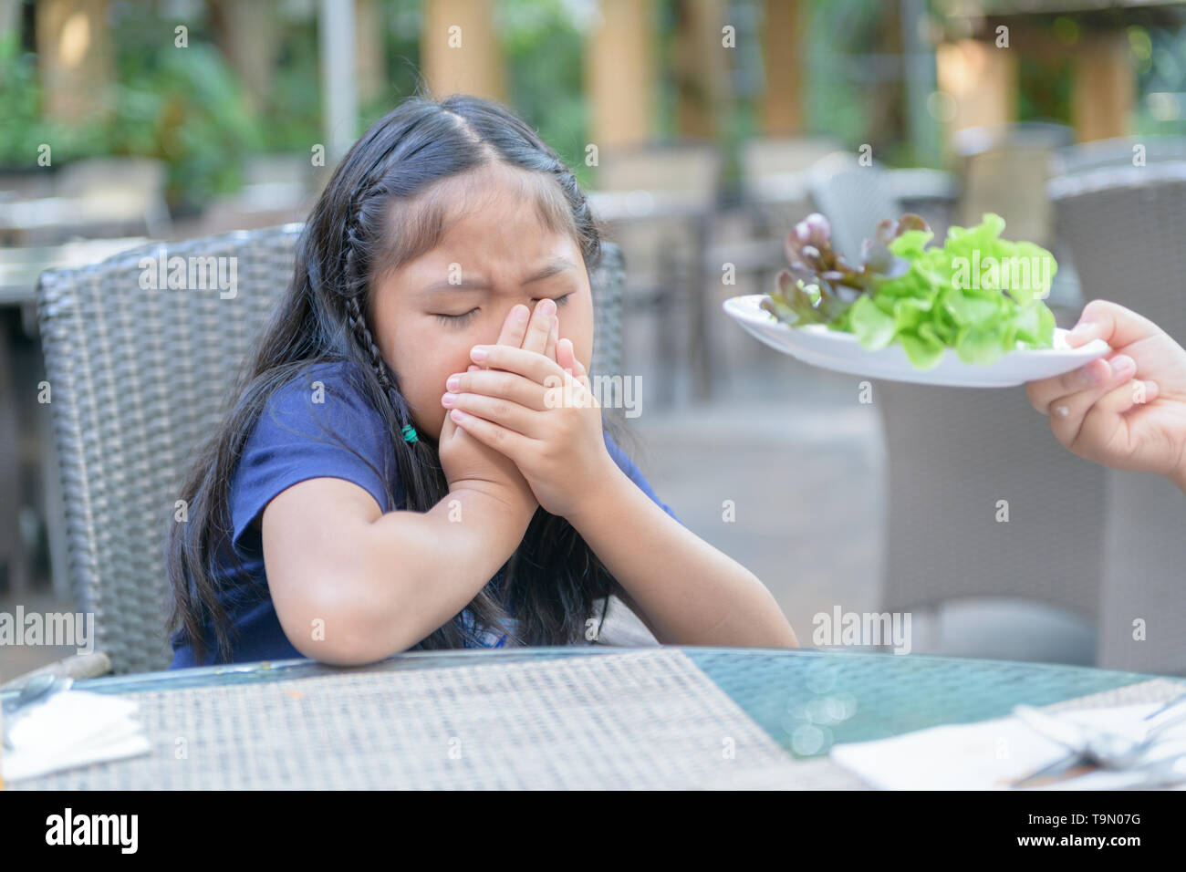 asian child girl with expression of disgust against vegetables in salad ...