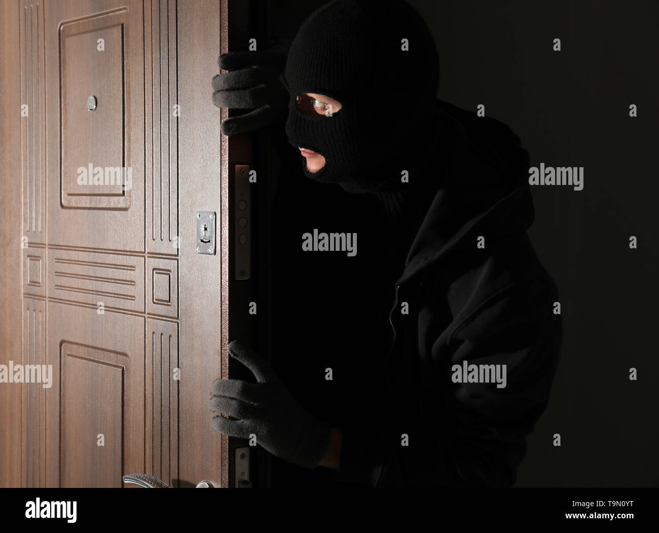 Male thief entering house through door at night Stock Photo - Alamy