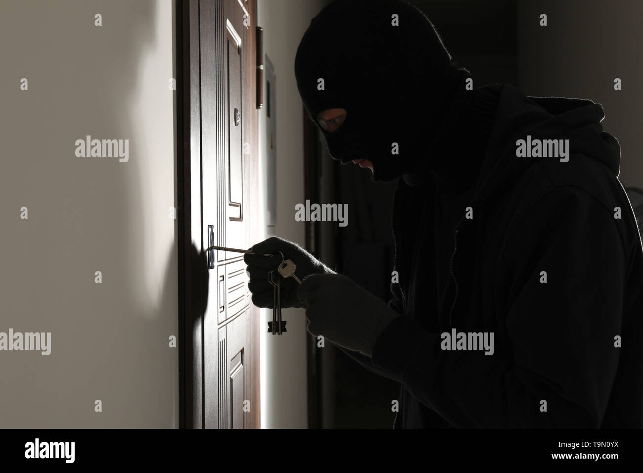 Male thief opening door with keys indoors Stock Photo - Alamy