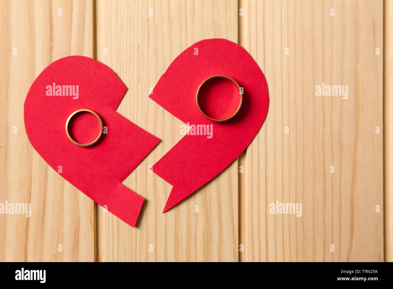 Broken red heart with rings on wooden background. Concept of divorce ...