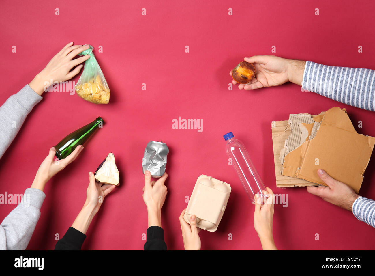 Many hands with different types of garbage on color background. Ecology ...