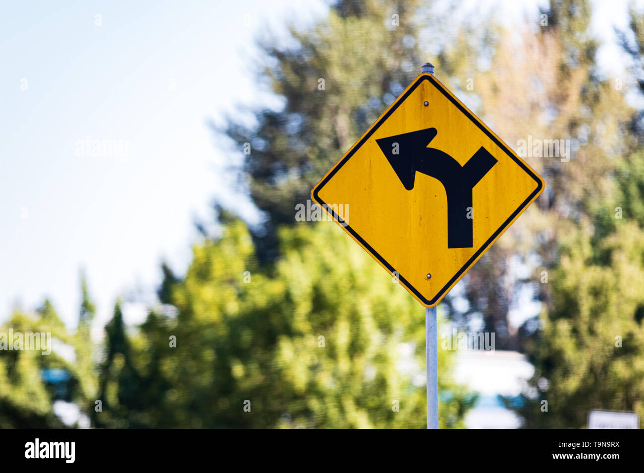Road turns directional street sign with trees in the background Stock ...