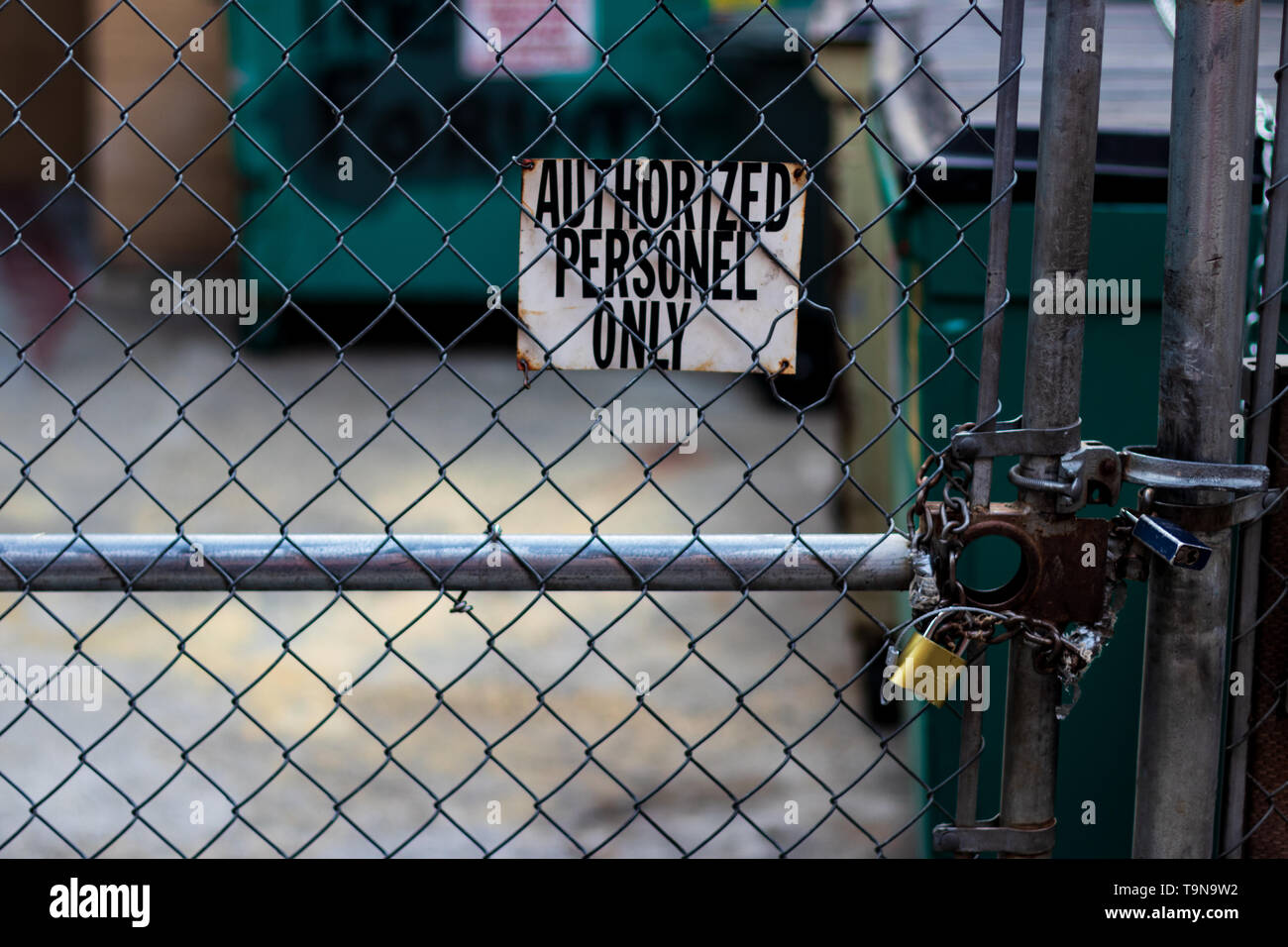 Authorized personnel sign on a chain link fence with dumpsters in the ...