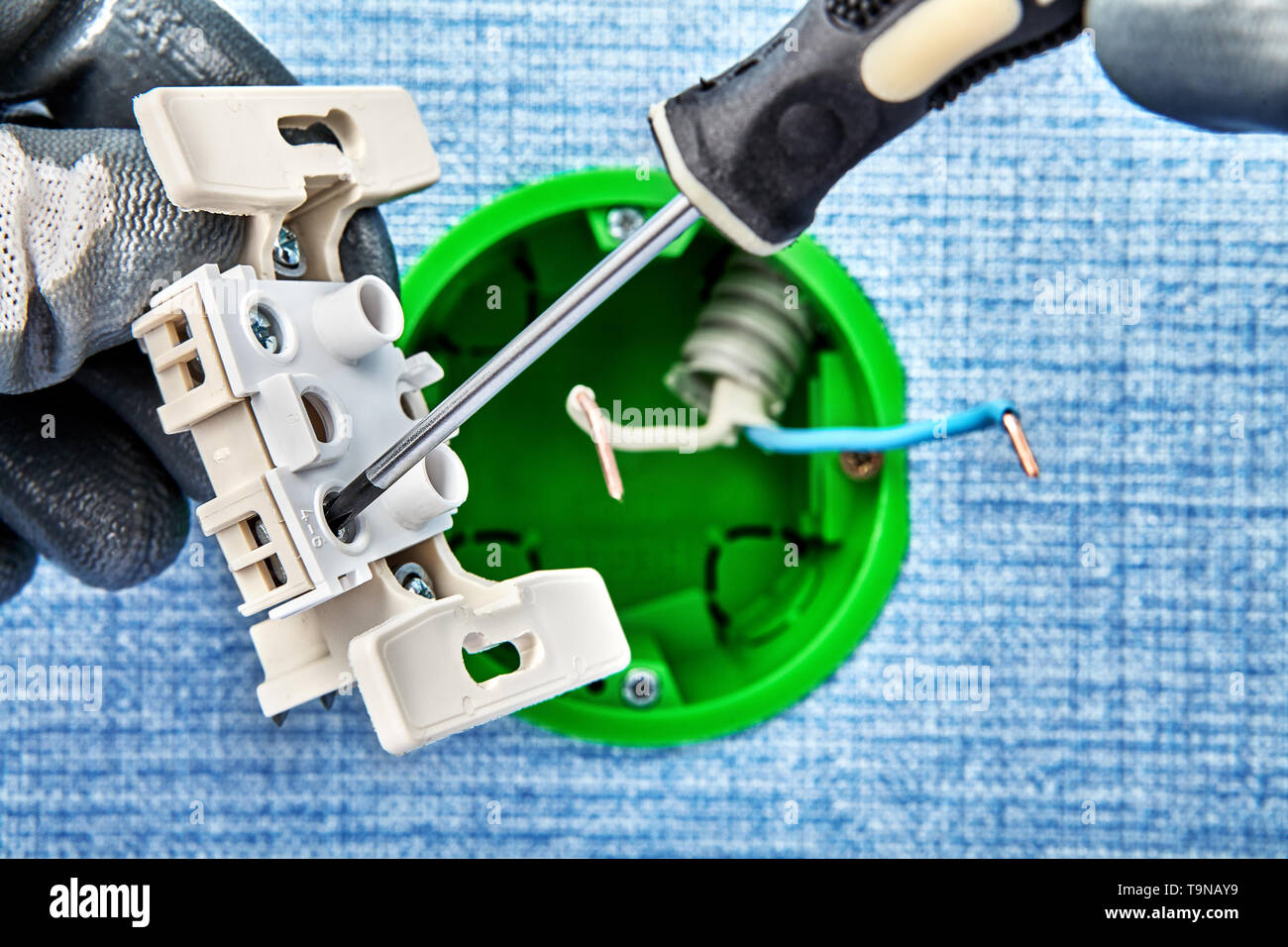 Worker in protective gloves is twisting screw in the part of new round ...