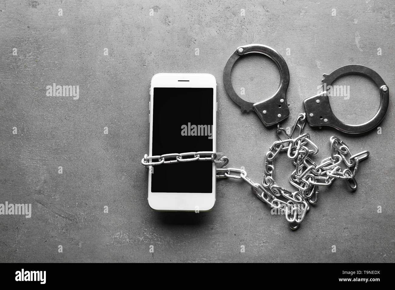 Chained mobile phone with handcuffs on grey table. Concept of addiction ...