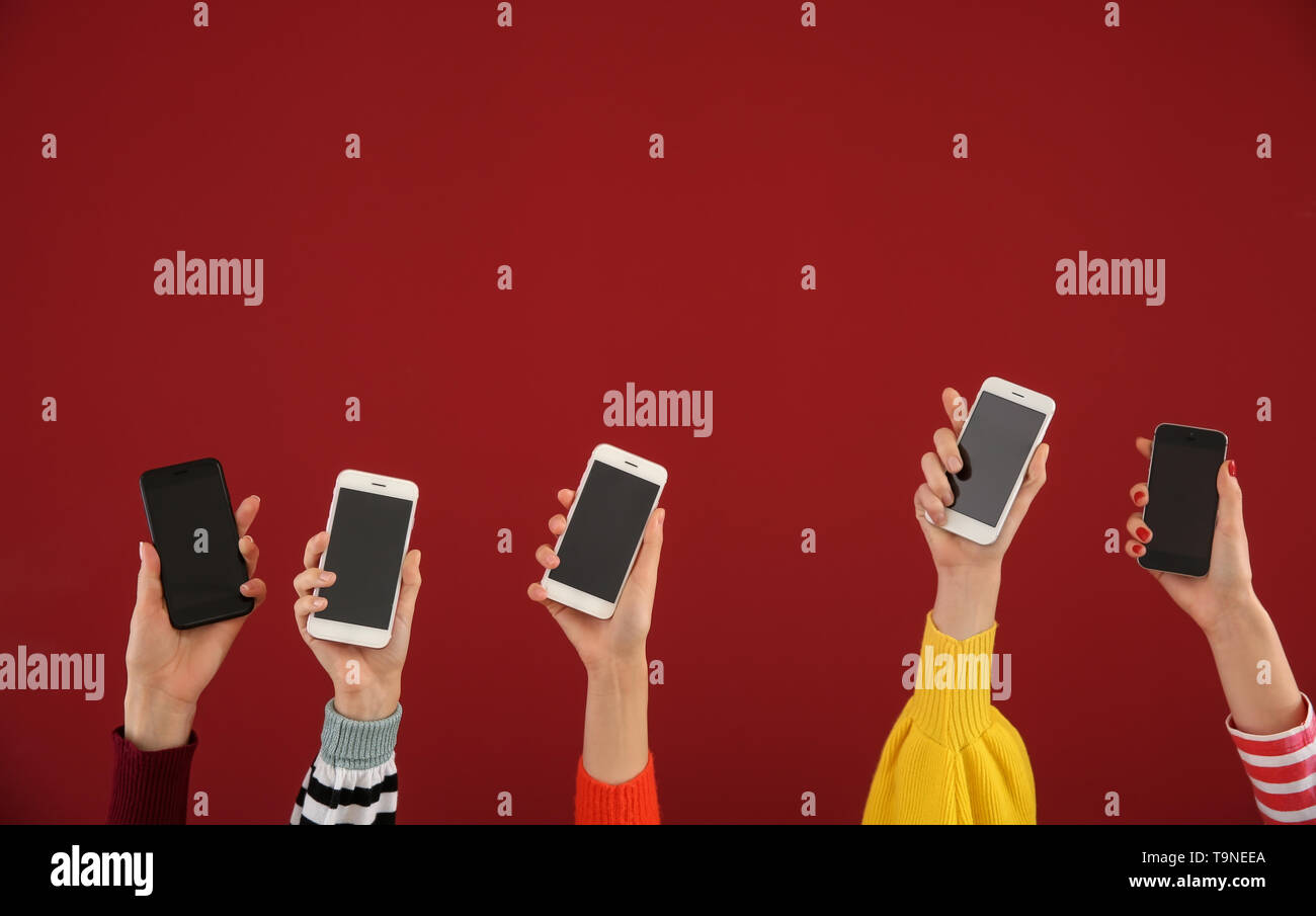 Young people holding mobile phones on color background. Concept of ...