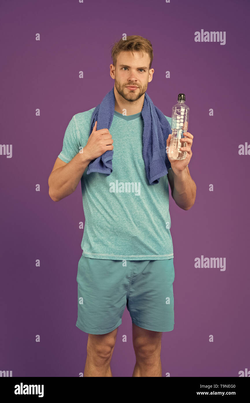 Stay hydrated. Man with towel on shoulders hold bottle. Athlete drink ...