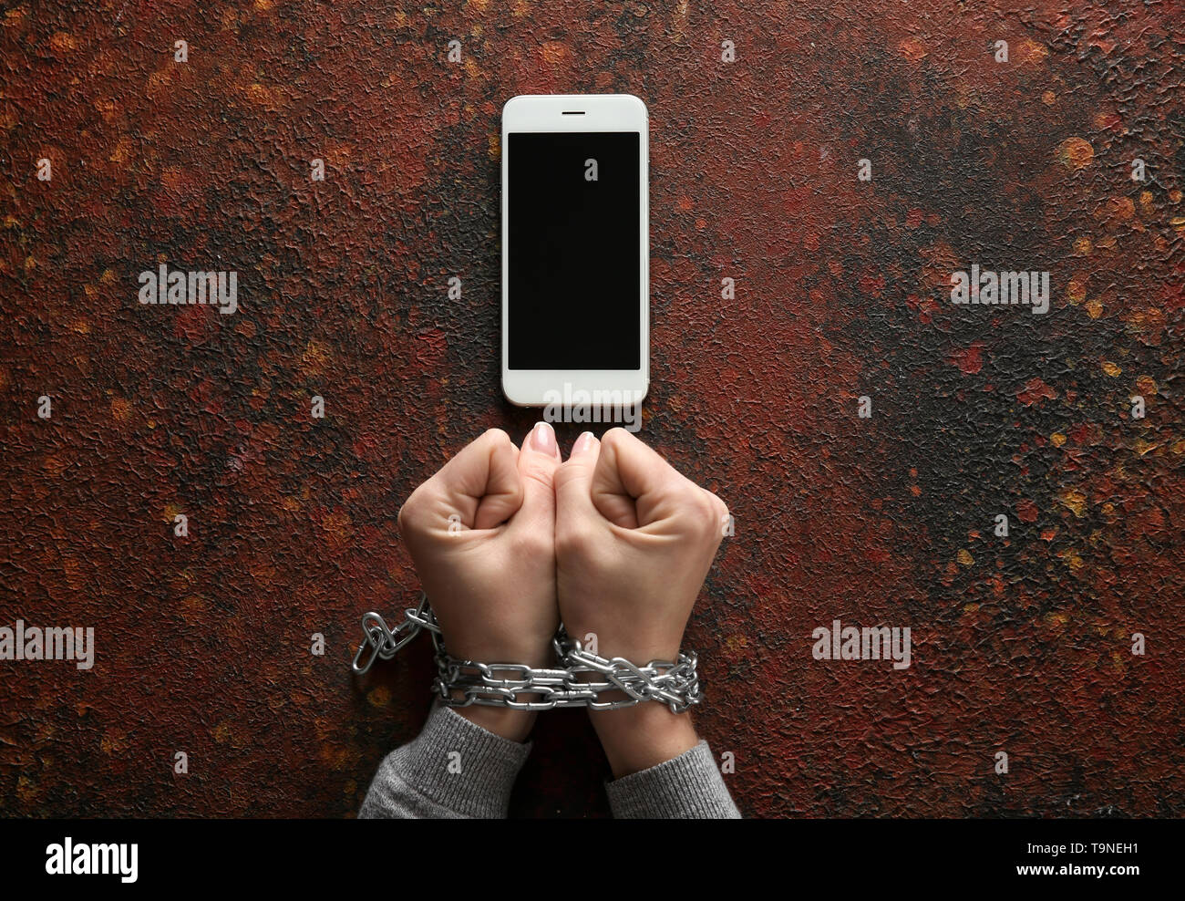 Woman with chained hands and mobile phone on color background. Concept ...