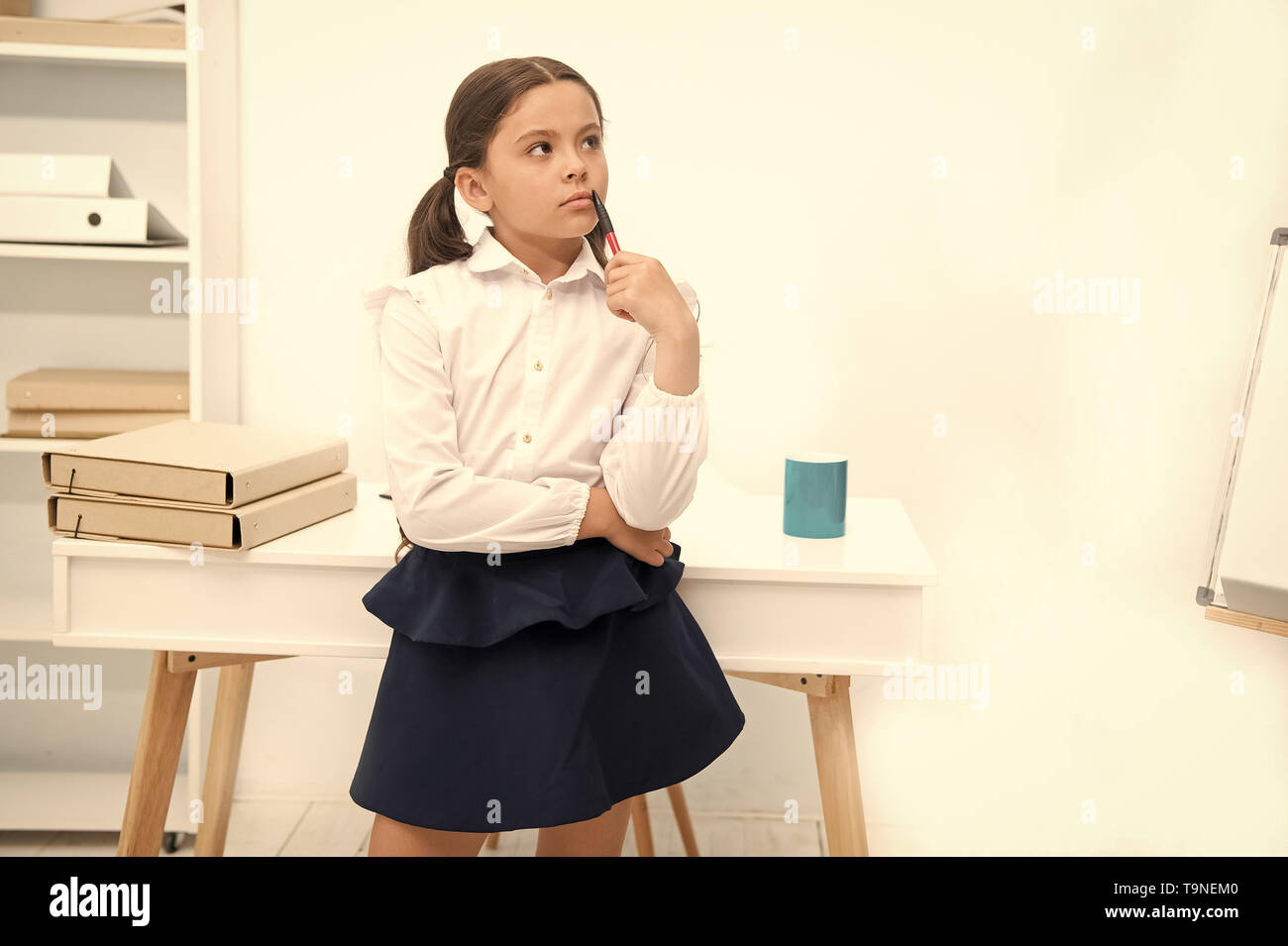 Focused on remembering. Child girl wears school uniform standing with ...