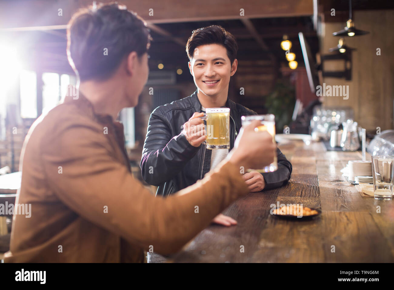 Happy young men drinking beer in bar Stock Photo - Alamy