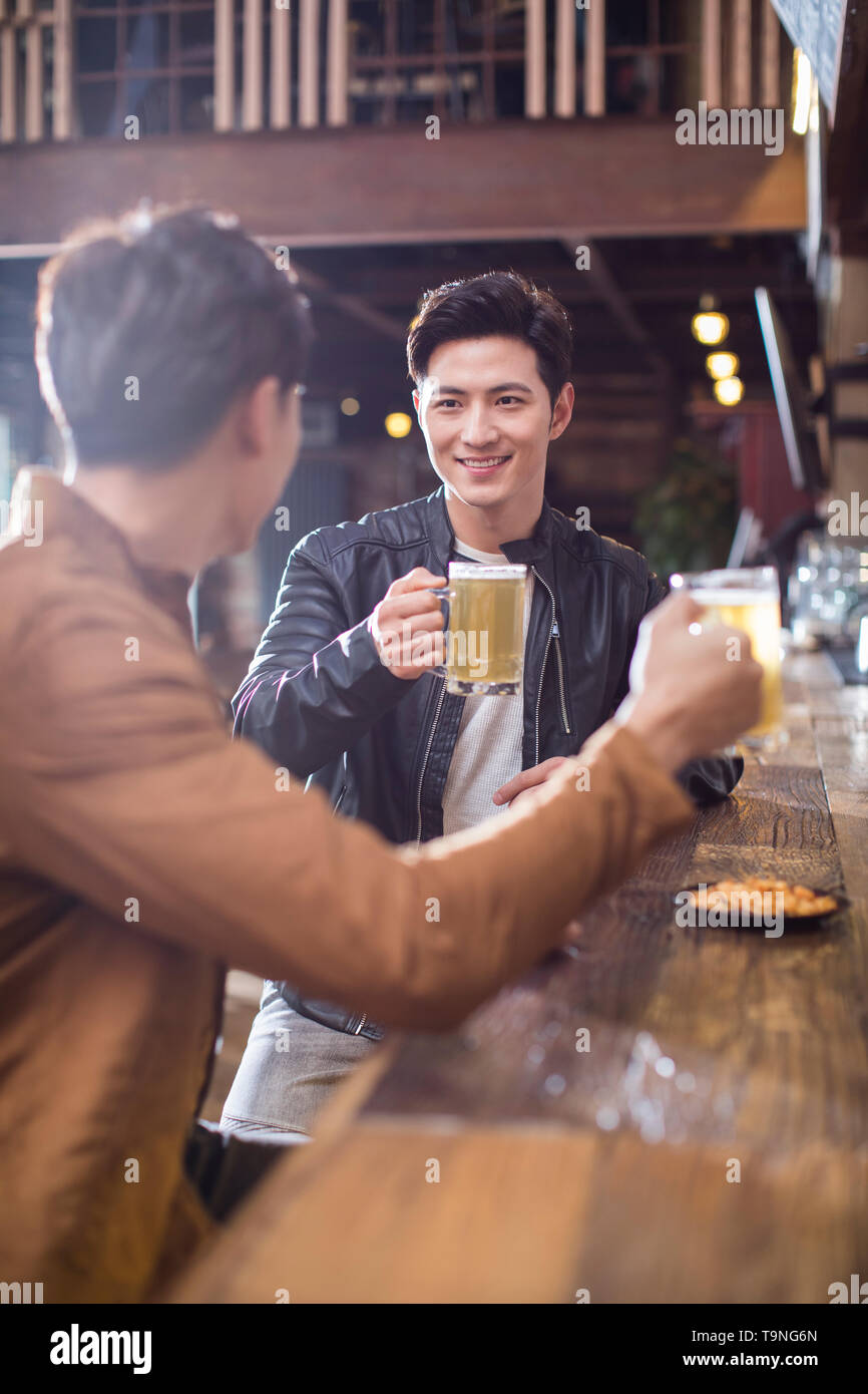Happy young men drinking beer in bar Stock Photo - Alamy