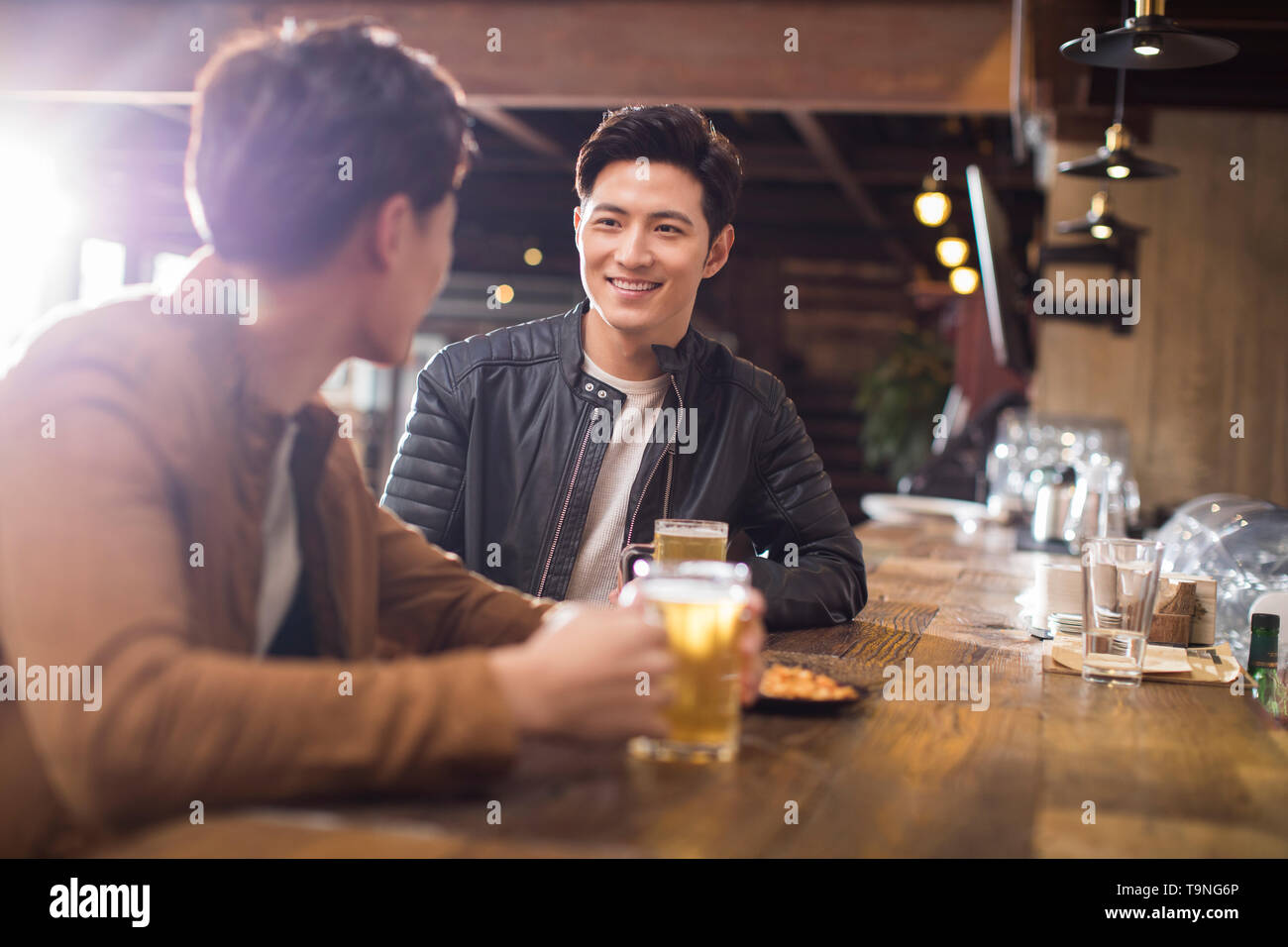 Happy young men drinking beer in bar Stock Photo - Alamy