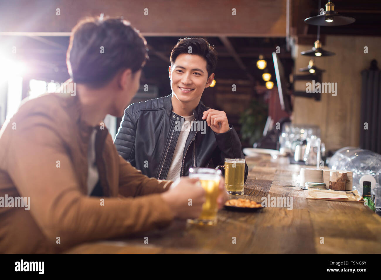 Happy young men drinking beer in bar Stock Photo - Alamy