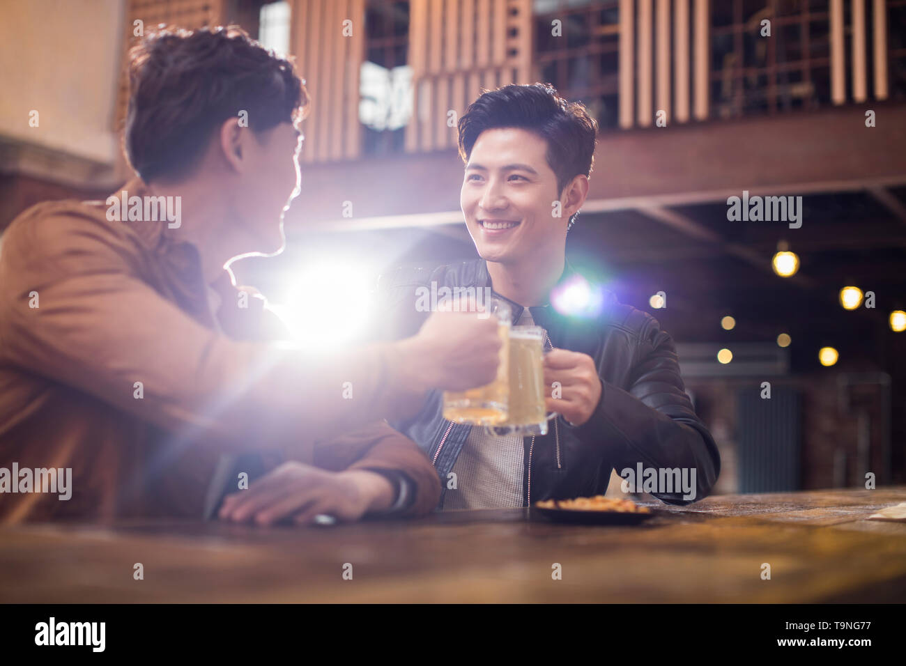Happy young men toasting in bar Stock Photo - Alamy