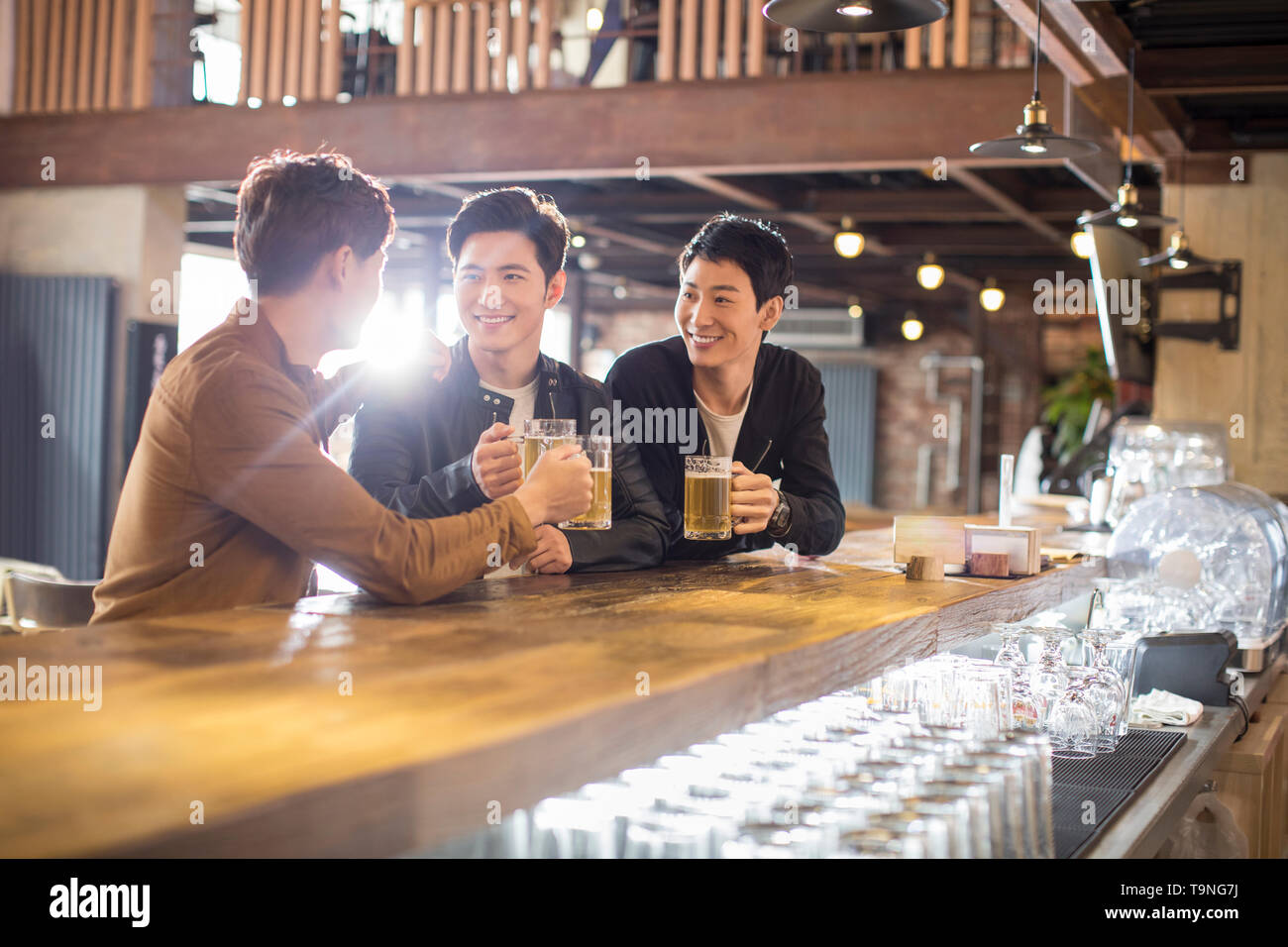Happy young men drinking in bar Stock Photo - Alamy