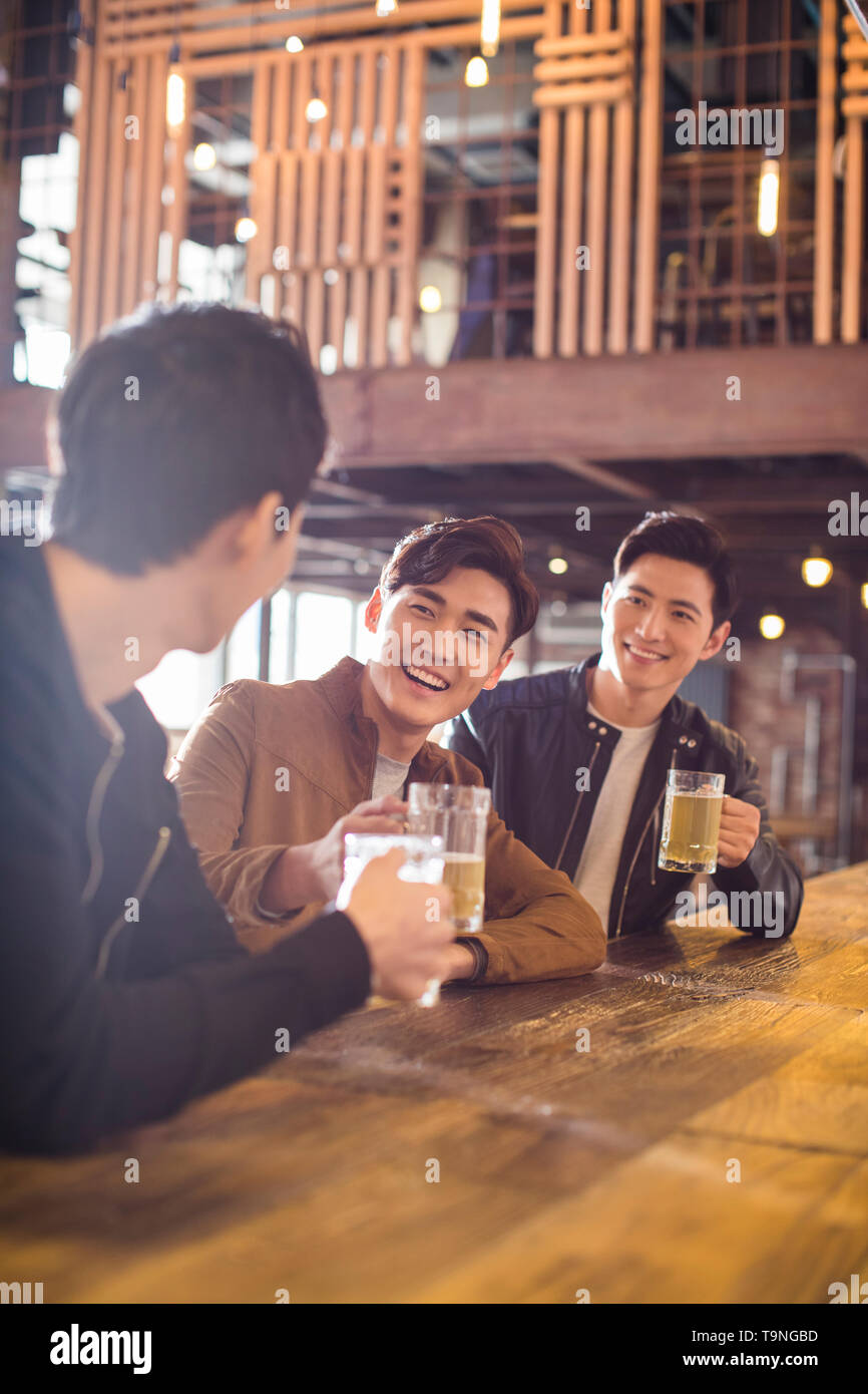 Happy young men drinking beer in bar Stock Photo - Alamy