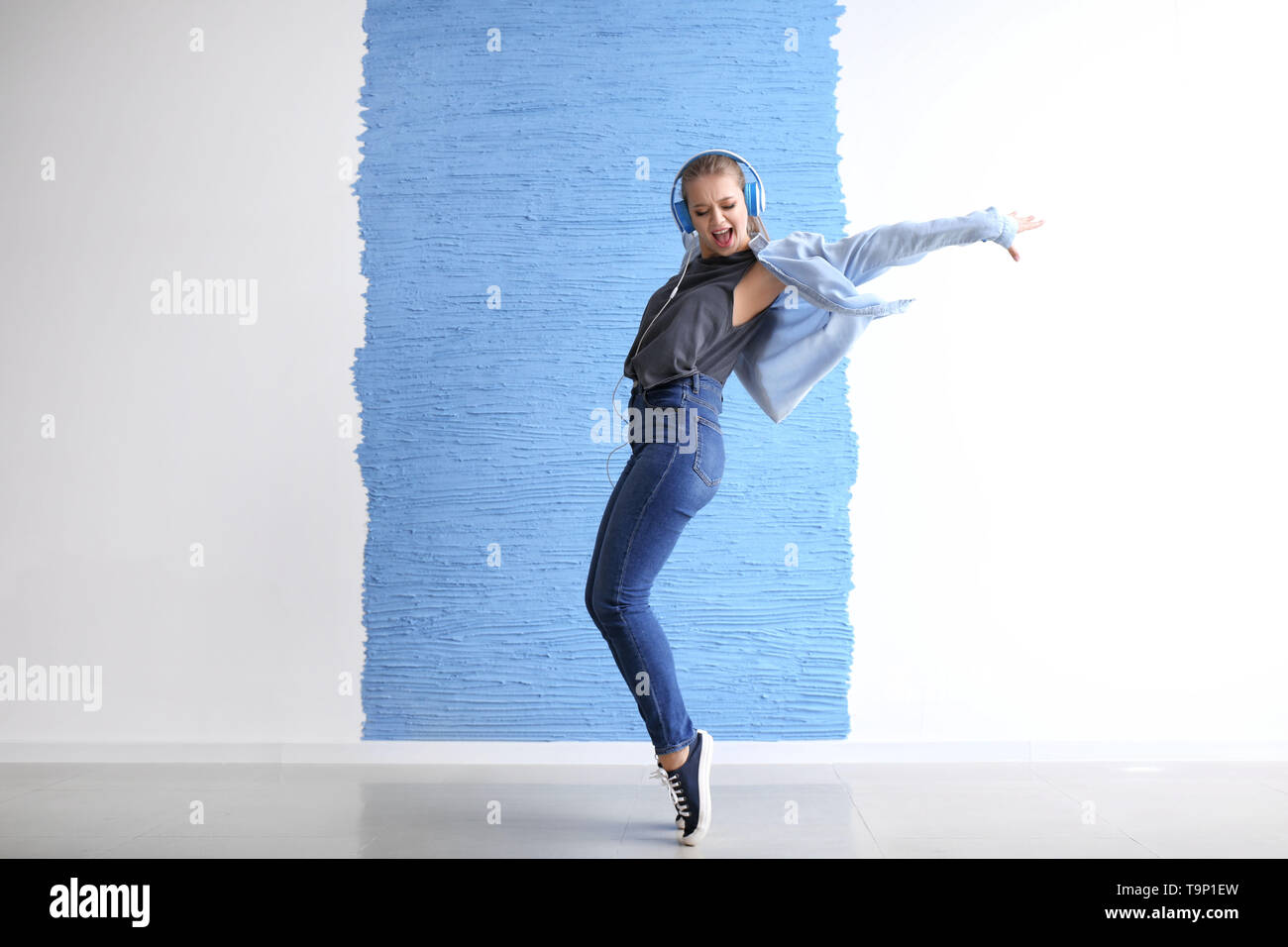 Beautiful young woman dancing against color wall Stock Photo - Alamy