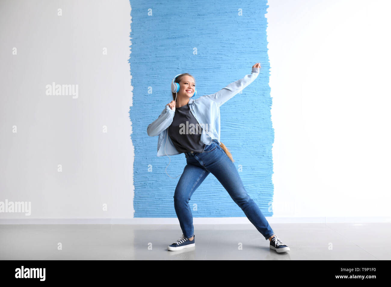Beautiful young woman dancing against color wall Stock Photo - Alamy