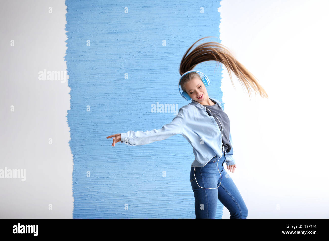 Beautiful young woman dancing against color wall Stock Photo - Alamy
