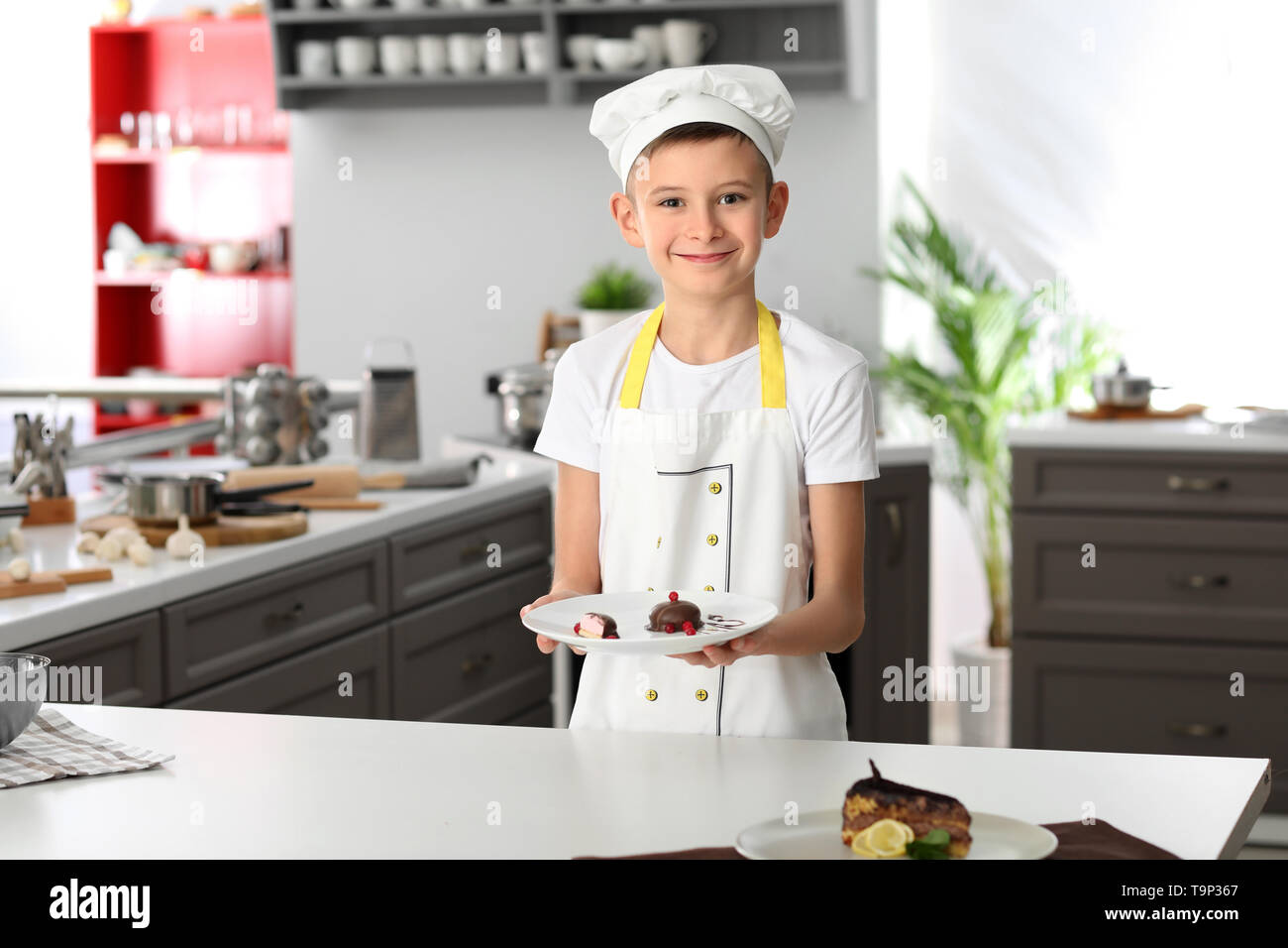 Cute little chef with tasty dessert in kitchen Stock Photo - Alamy